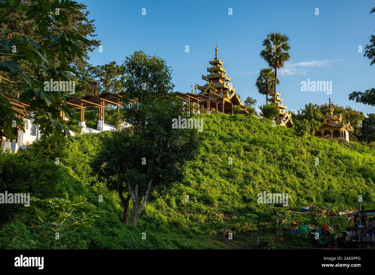 An elaborate Buddhist temple perched atop a tree filled hill and facing ...