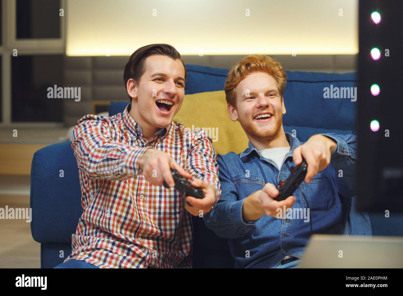 Young men having party indoors fun together playing football game on ...