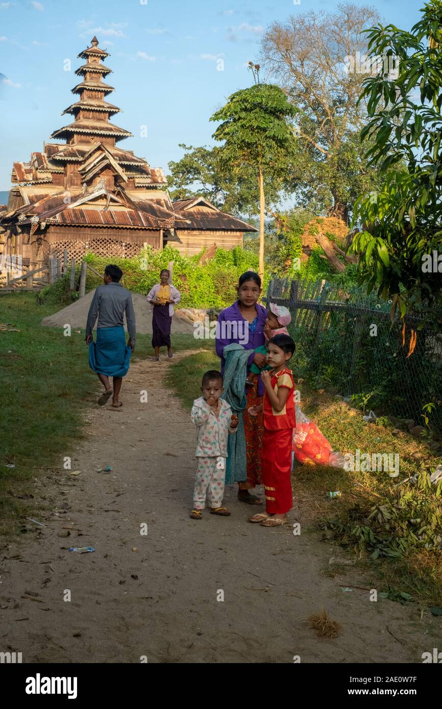 A Burmese mother and her three children and other villagers walk along ...