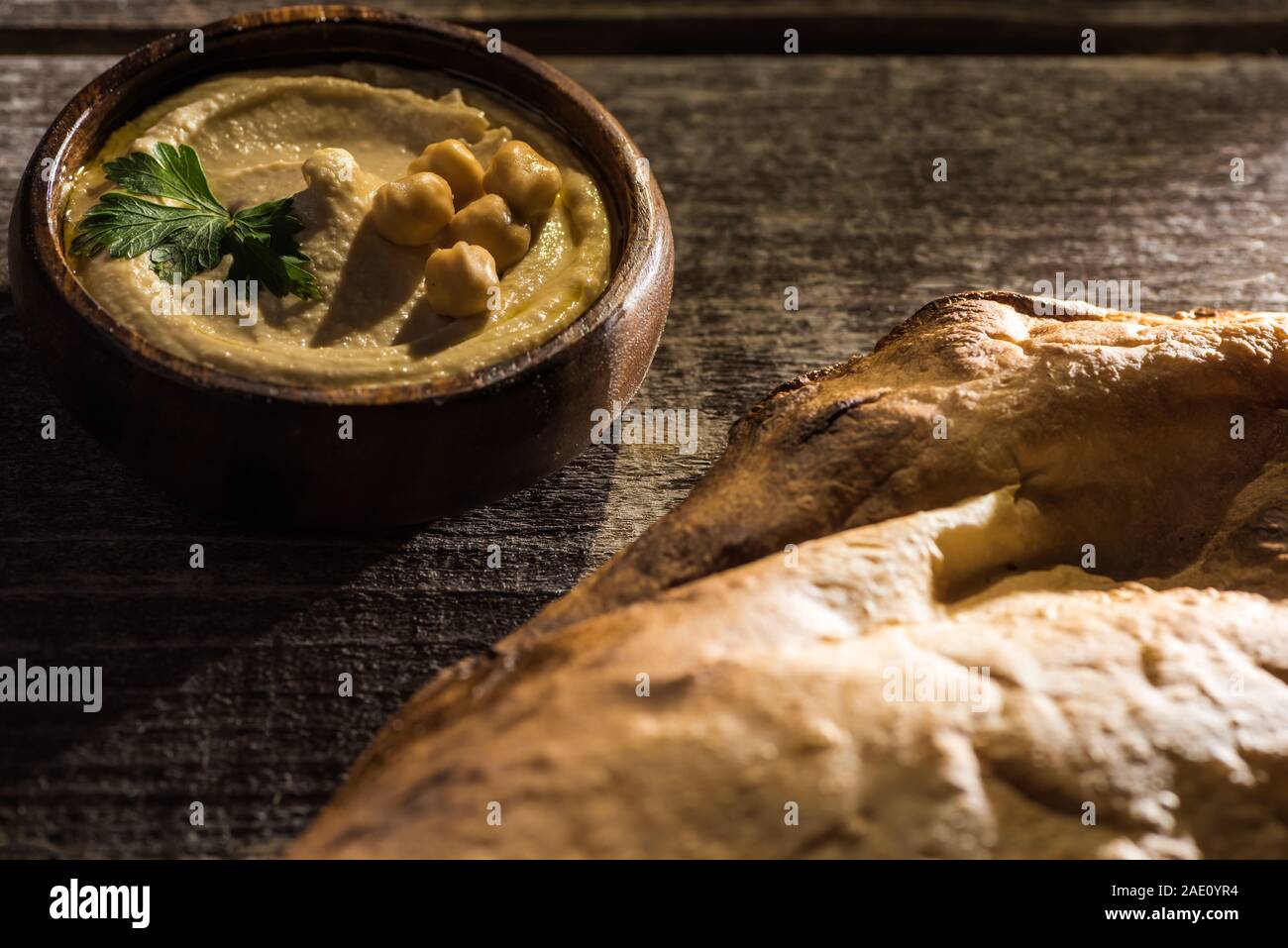 delicious hummus with chickpeas in bowl near fresh baked pita on wooden ...