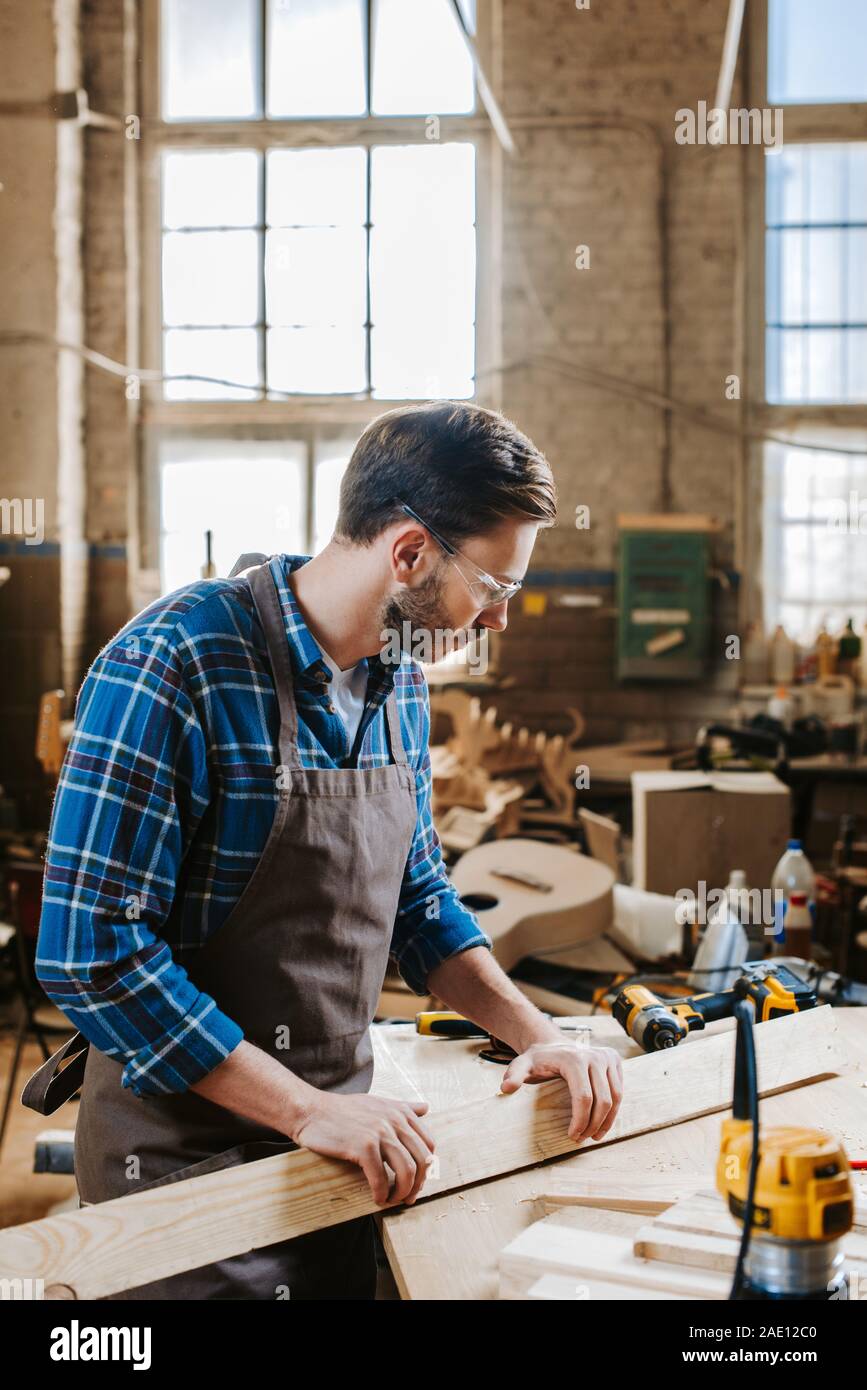 selective focus of bearded woodworker holding plank in workshop Stock ...