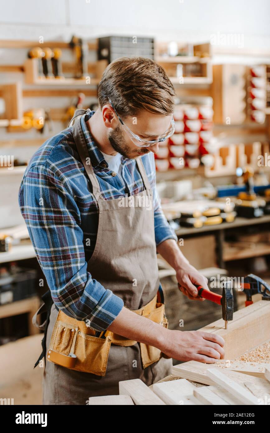 carpenter in goggles holding hammer near wooden dowel Stock Photo - Alamy