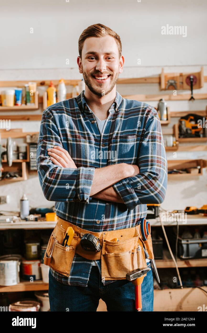 happy carpenter in apron standing with crossed arms Stock Photo - Alamy
