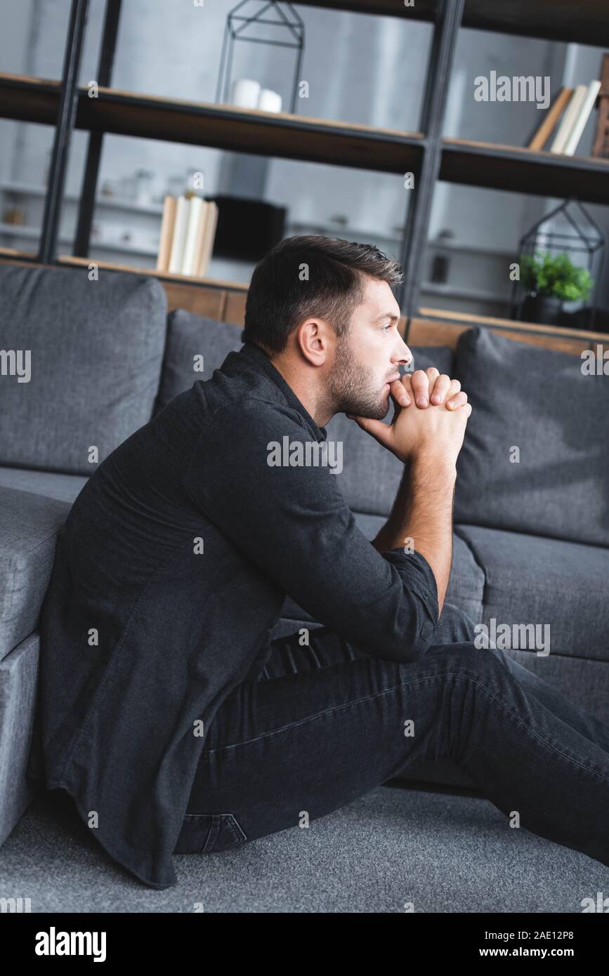 side view of handsome man with panic attack sitting on floor in ...