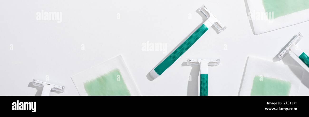 top view of green razors and depilation wax stripes on white background ...
