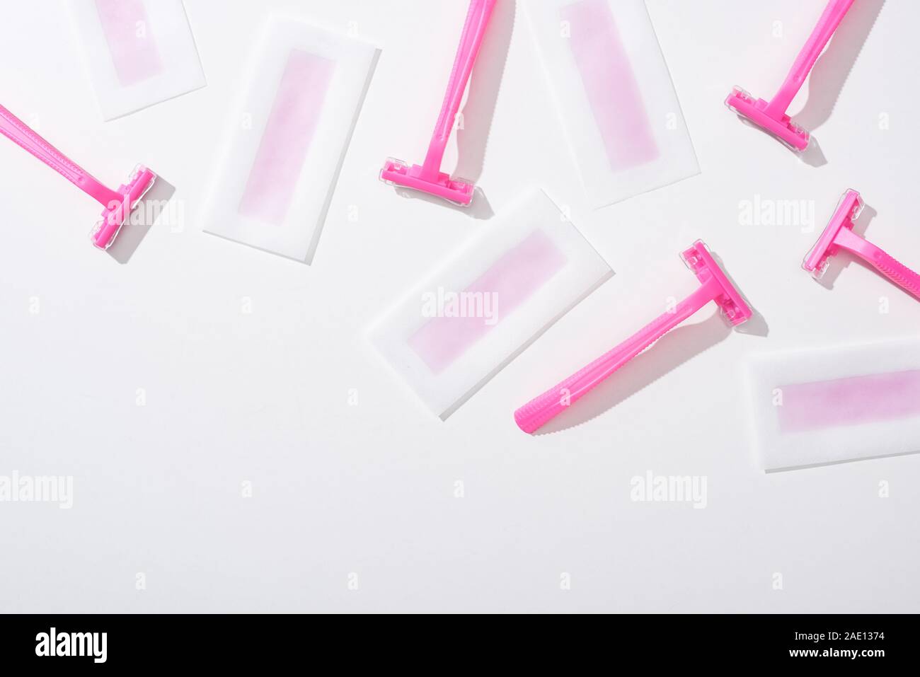top view of pink razors and depilation wax stripes on white background ...