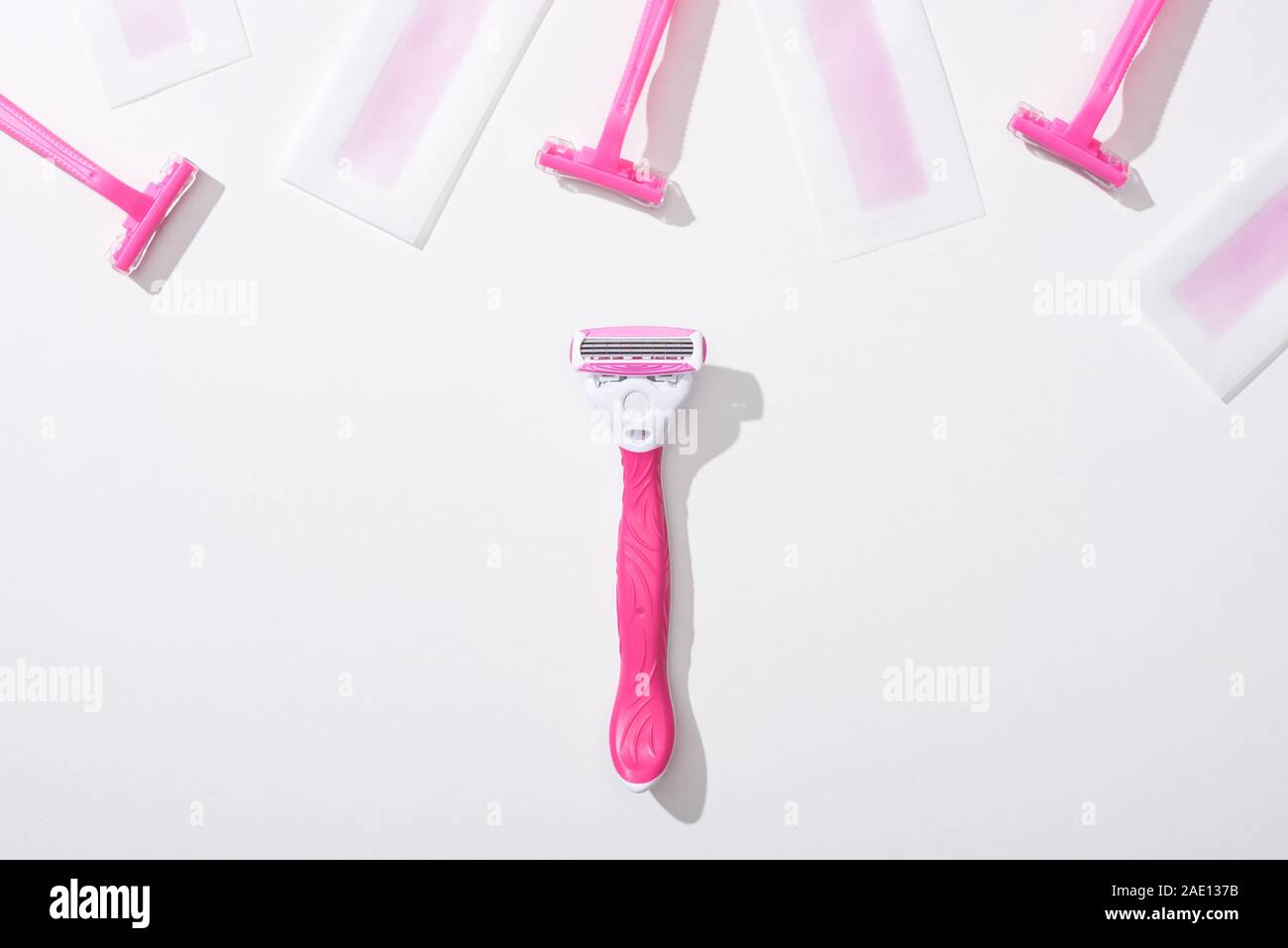 top view of pink razors and depilation wax stripes on white background ...