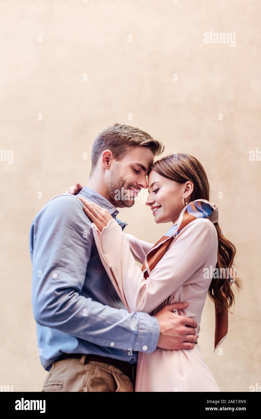 happy young couple embracing while standing face to face on street ...