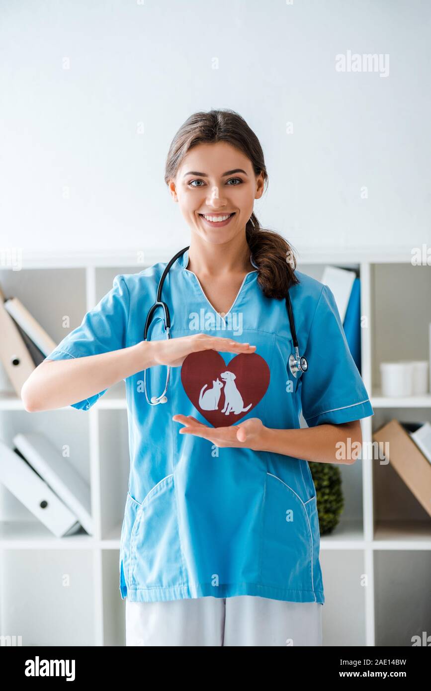 attractive, positive veterinarian smiling at camera while presenting ...