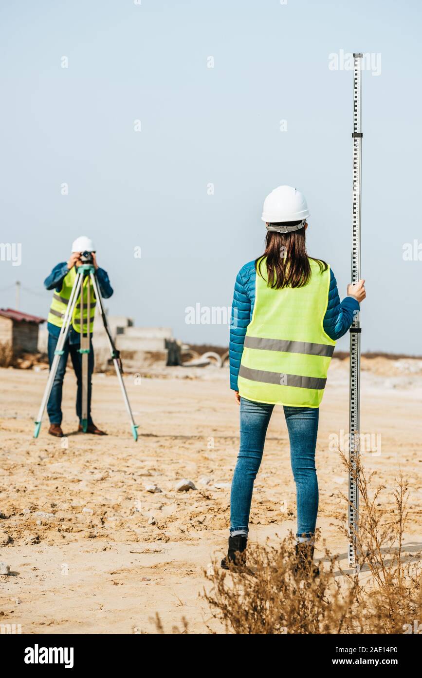 Selective focus of surveyors with survey ruler and digital level on ...