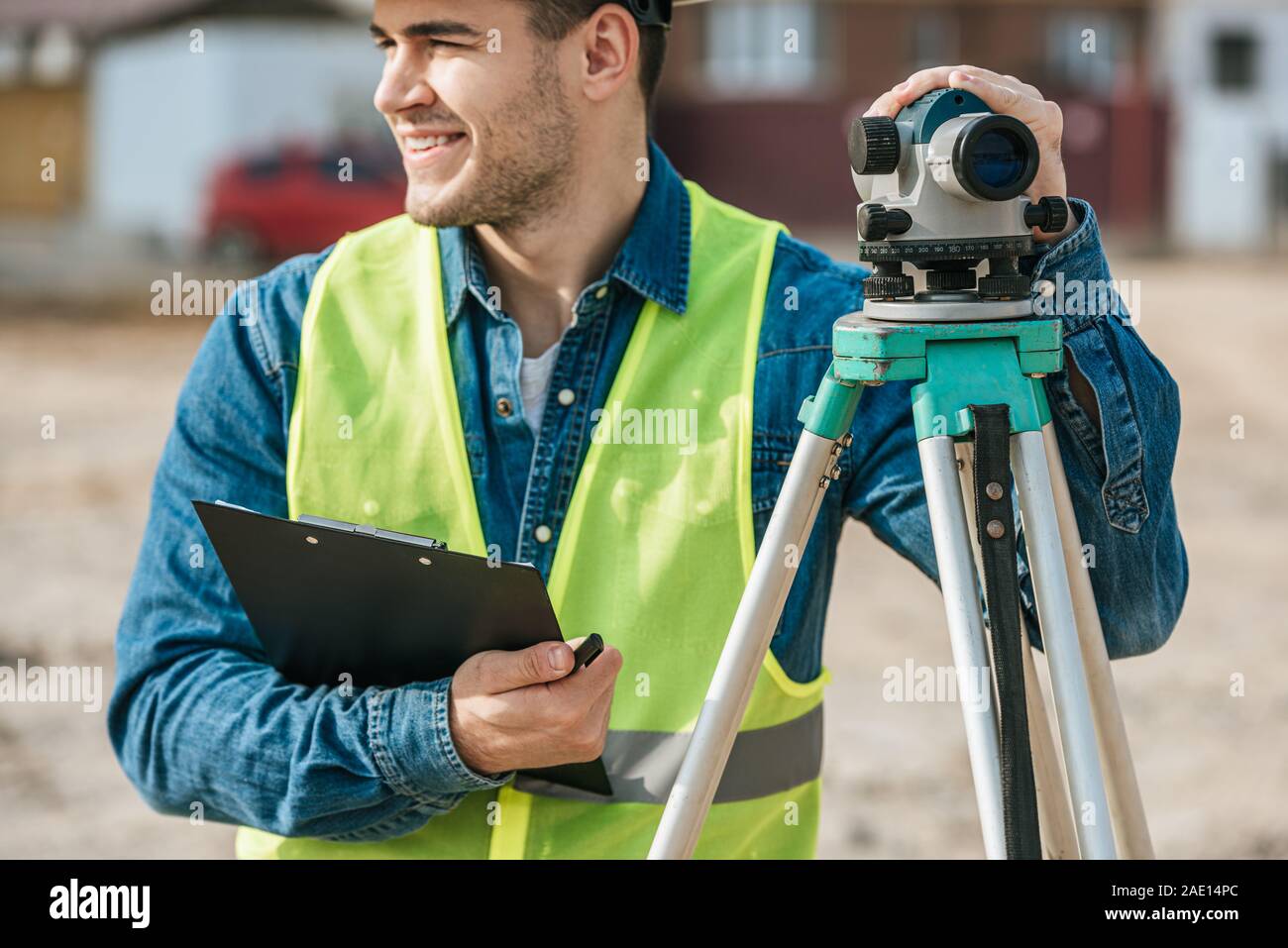 Smiling surveyor holding clipboard and digital level Stock Photo - Alamy