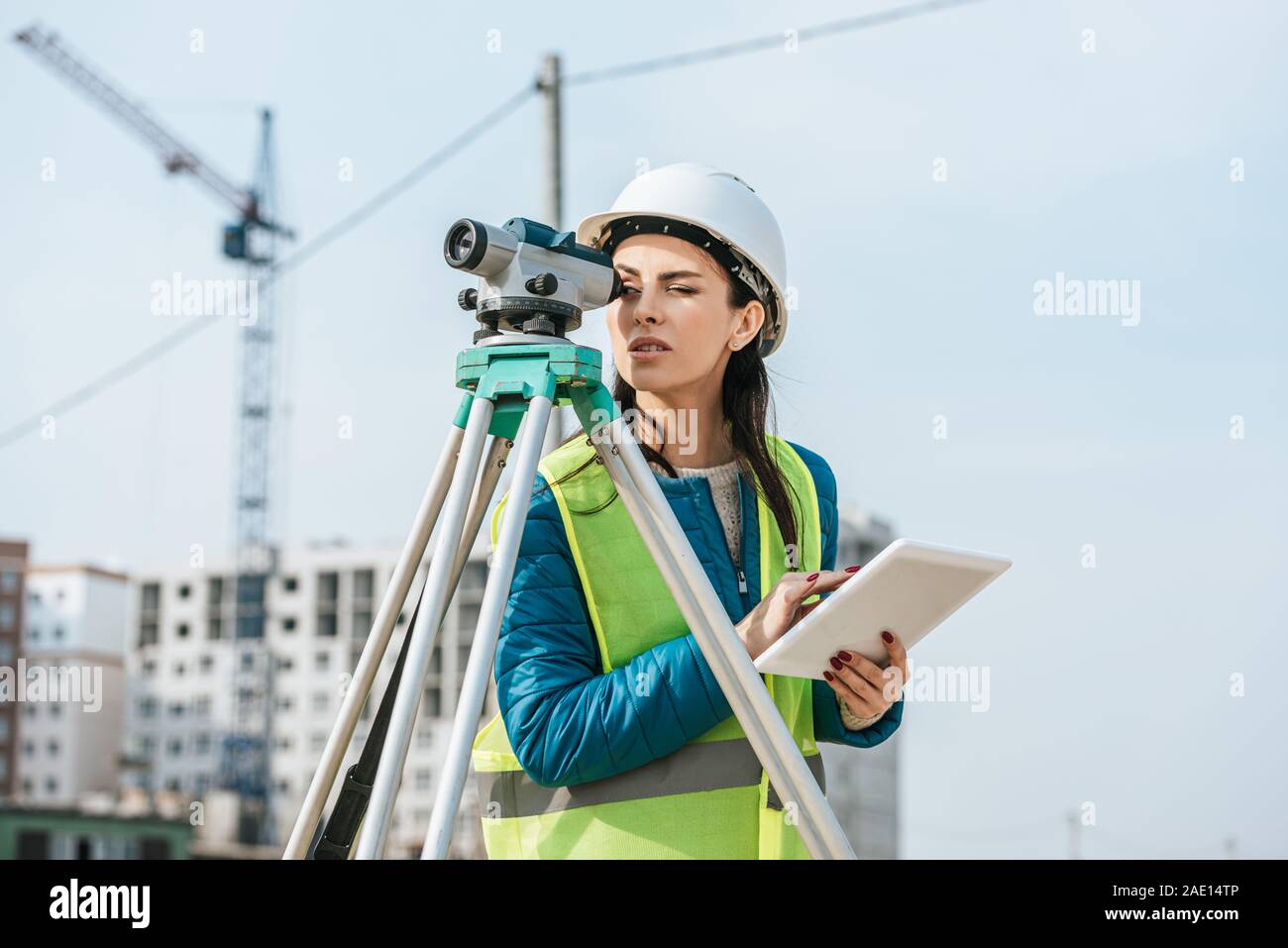 Surveyor with digital tablet looking through measuring level on ...