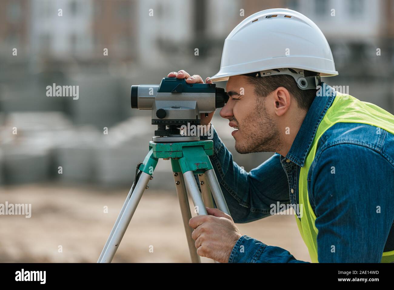 Side view of surveyor looking through digital level Stock Photo - Alamy