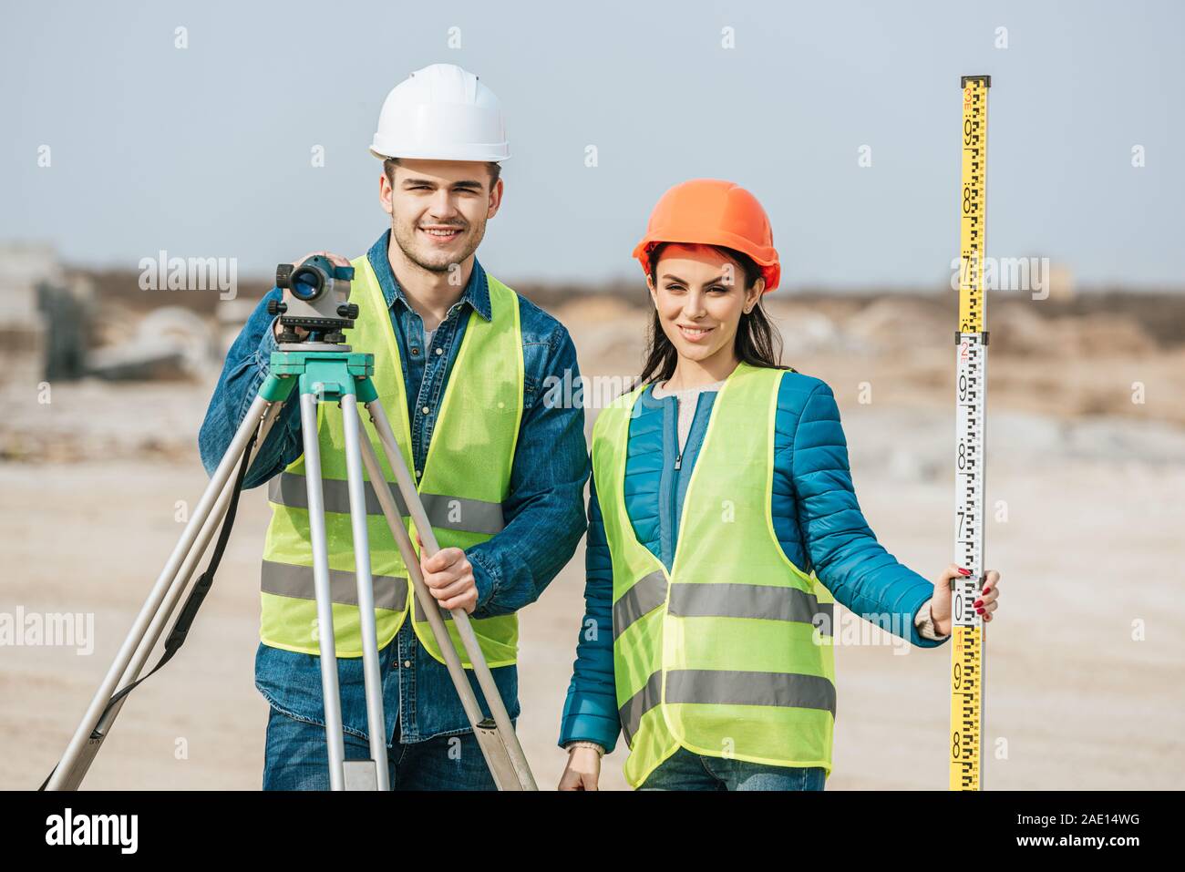 Smiling surveyors with ruler and digital level looking at camera Stock ...