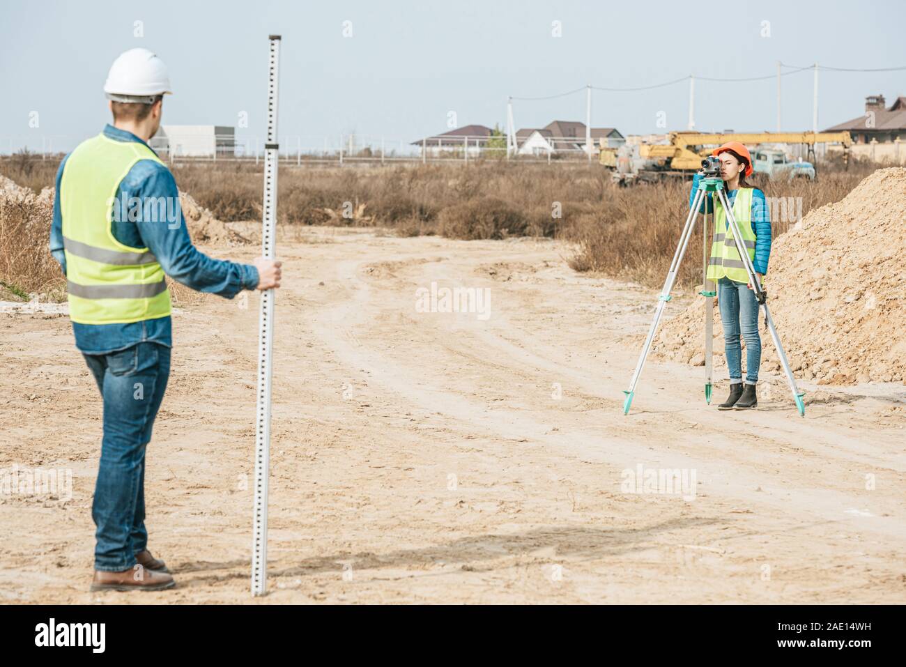 Surveyors with digital level and survey ruler working on dirt road ...