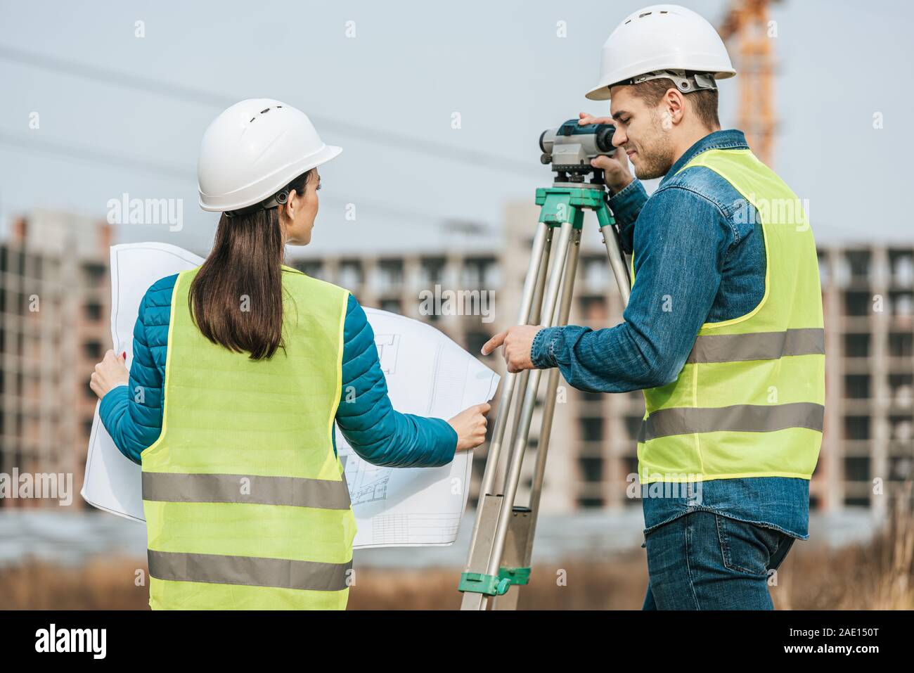Surveyors working with blueprint and digital level Stock Photo - Alamy