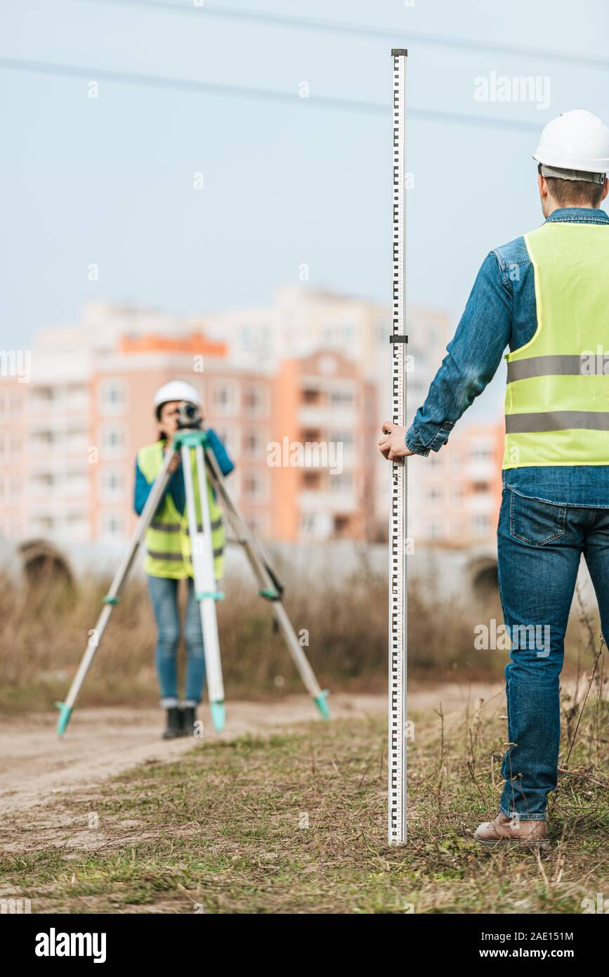 Selective focus of surveyors measuring land with digital level and ...