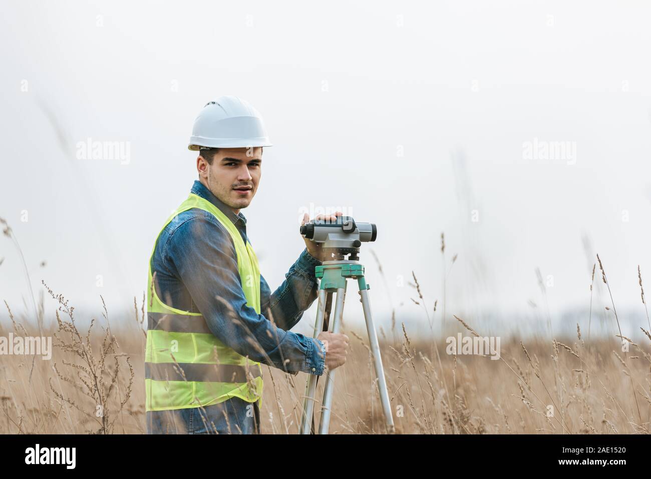 Surveyor with digital level looking at camera in field Stock Photo - Alamy