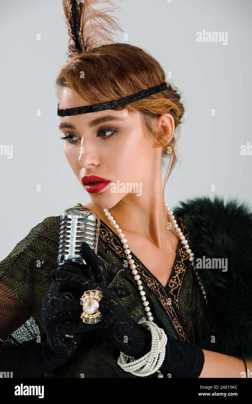 attractive singer touching retro microphone isolated on grey Stock ...