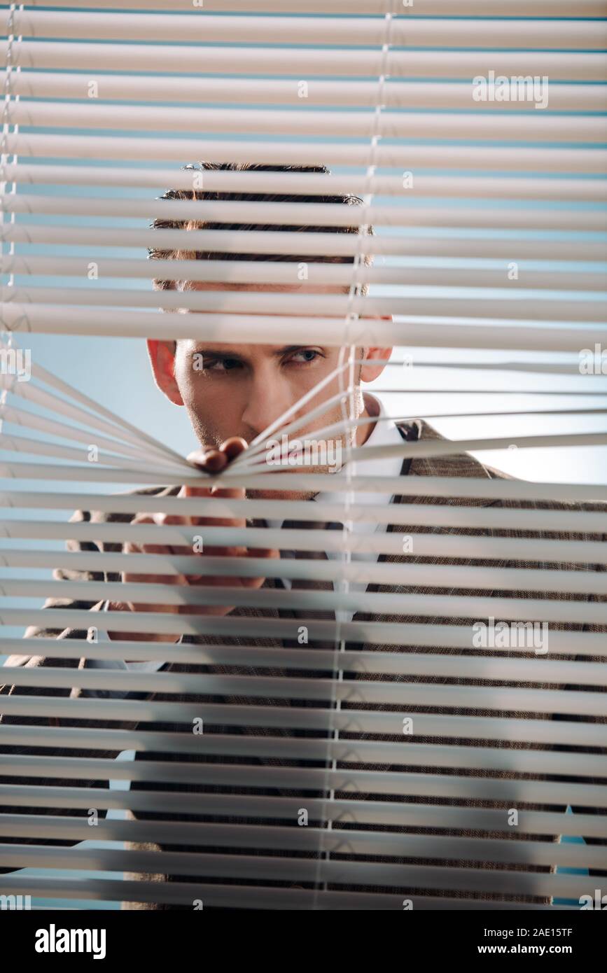 man touching window binds and looking away Stock Photo - Alamy