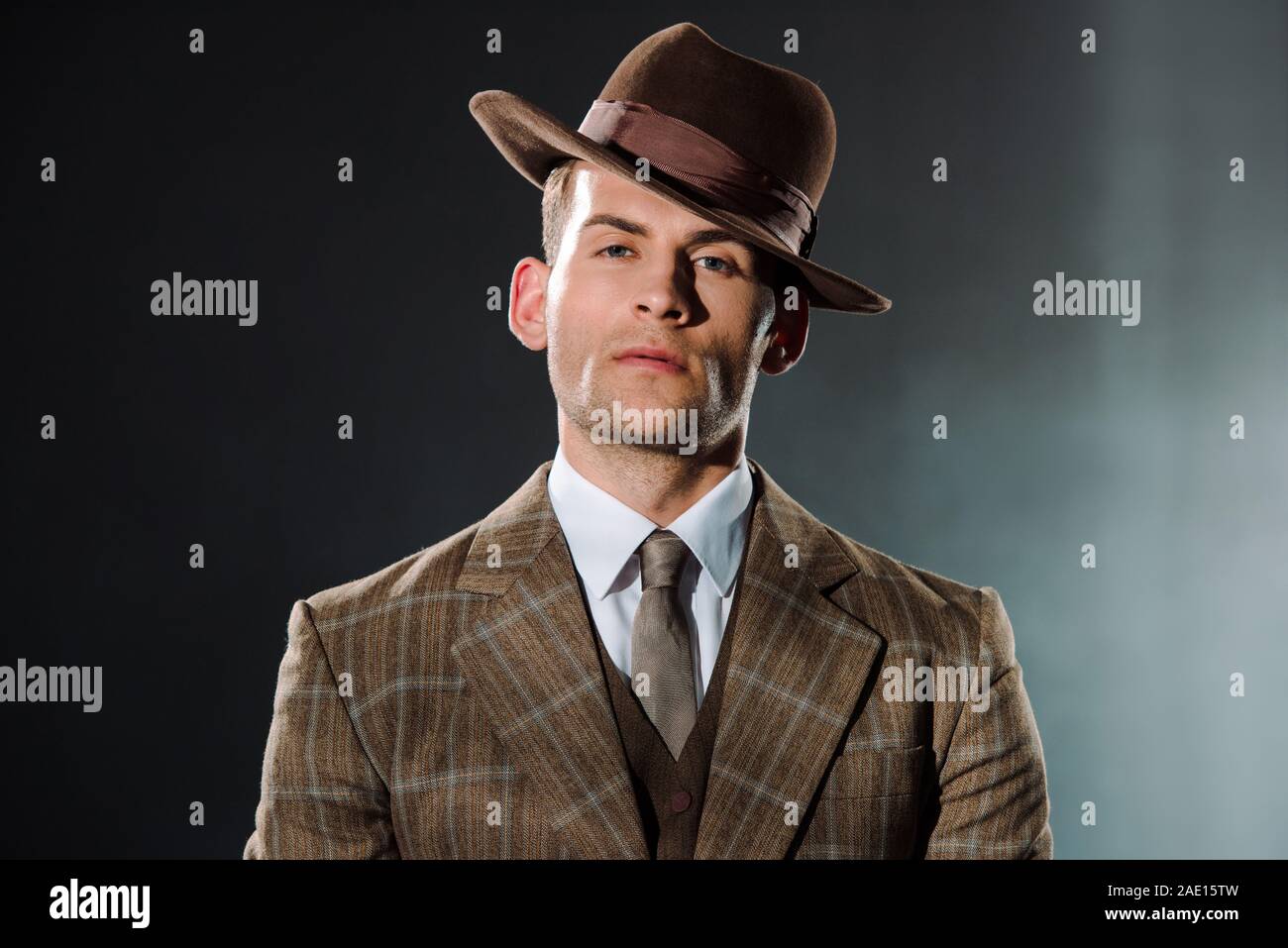stylish gangster in hat looking at camera on black Stock Photo - Alamy