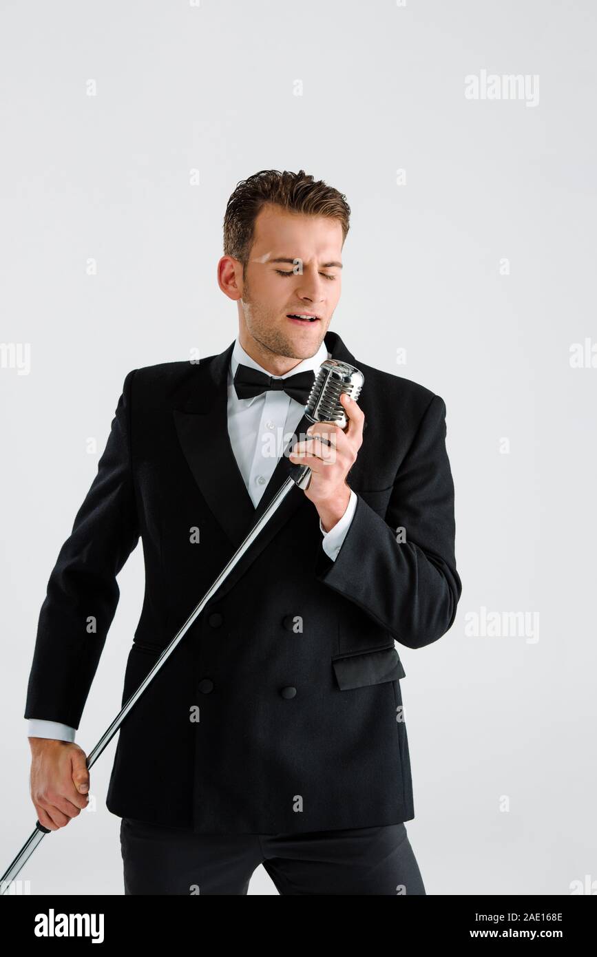 handsome man in suit touching retro microphone while singing isolated ...
