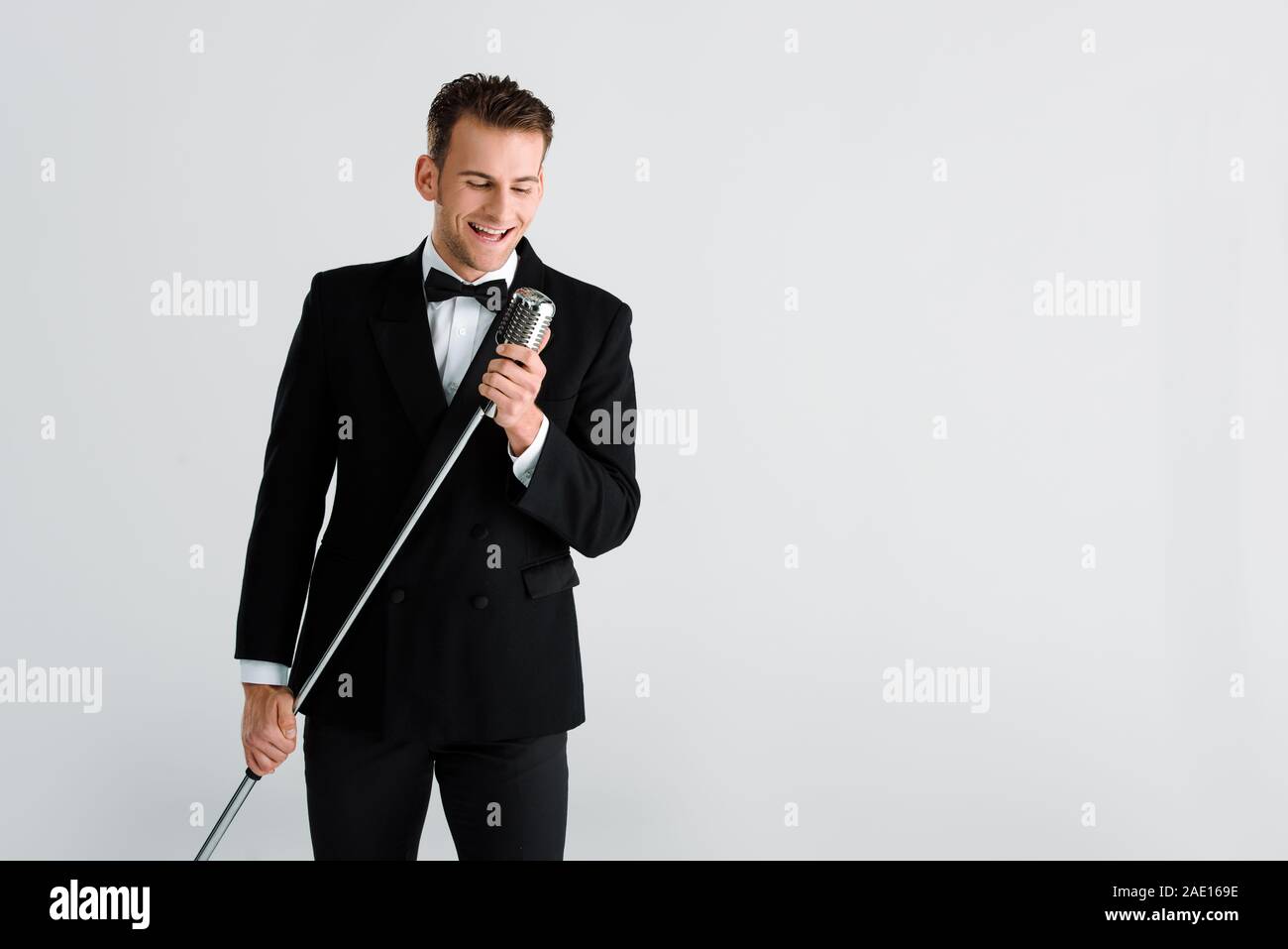 happy singer touching retro microphone isolated on grey Stock Photo - Alamy