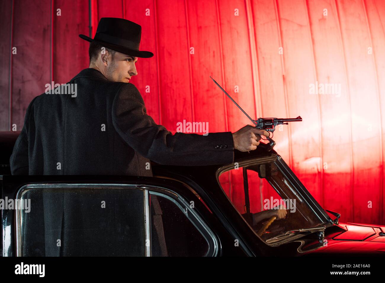 handsome gangster holding gun while standing near vintage car Stock ...
