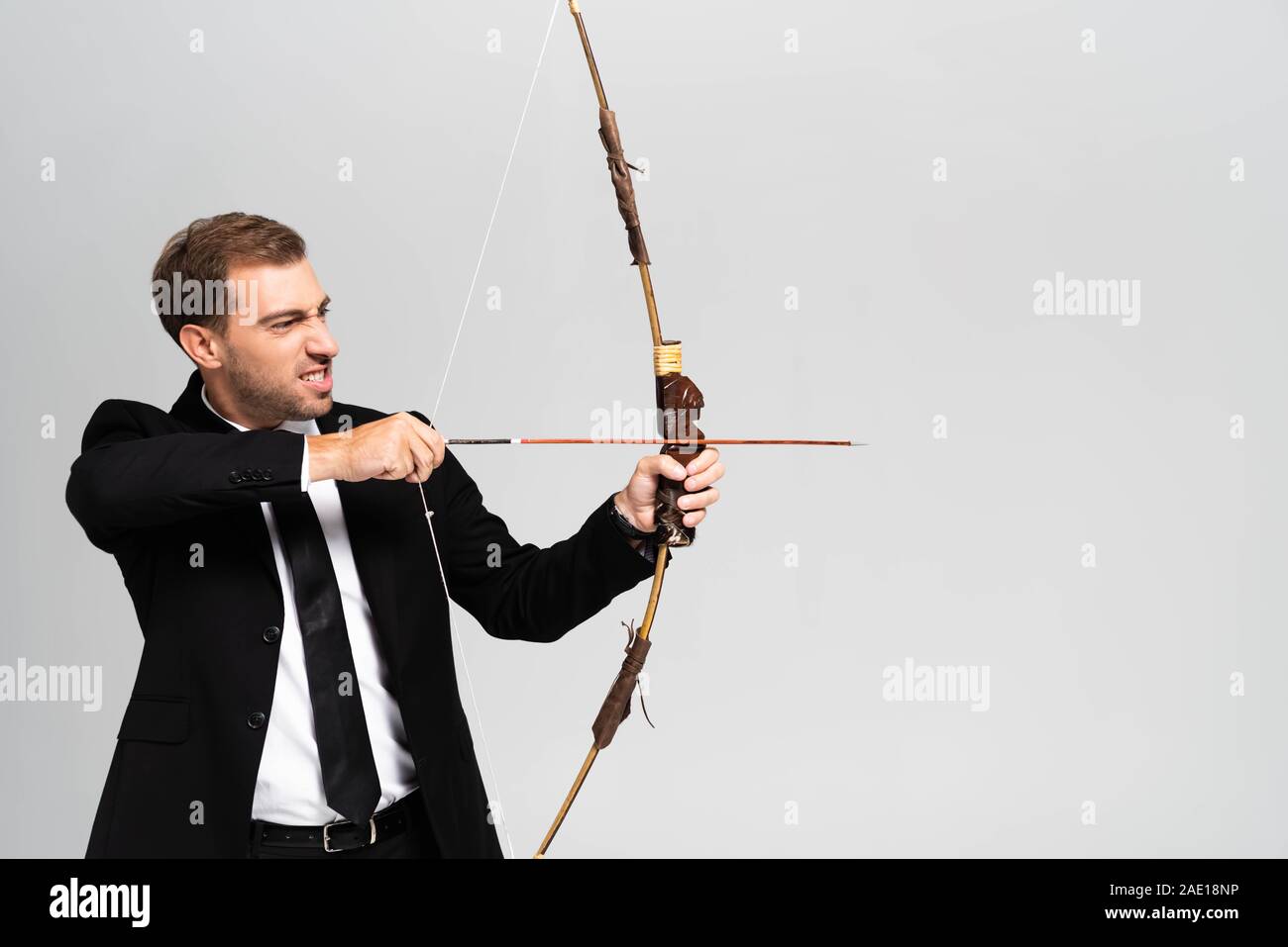 angry businessman in suit holding bow and shooting with arrow isolated ...