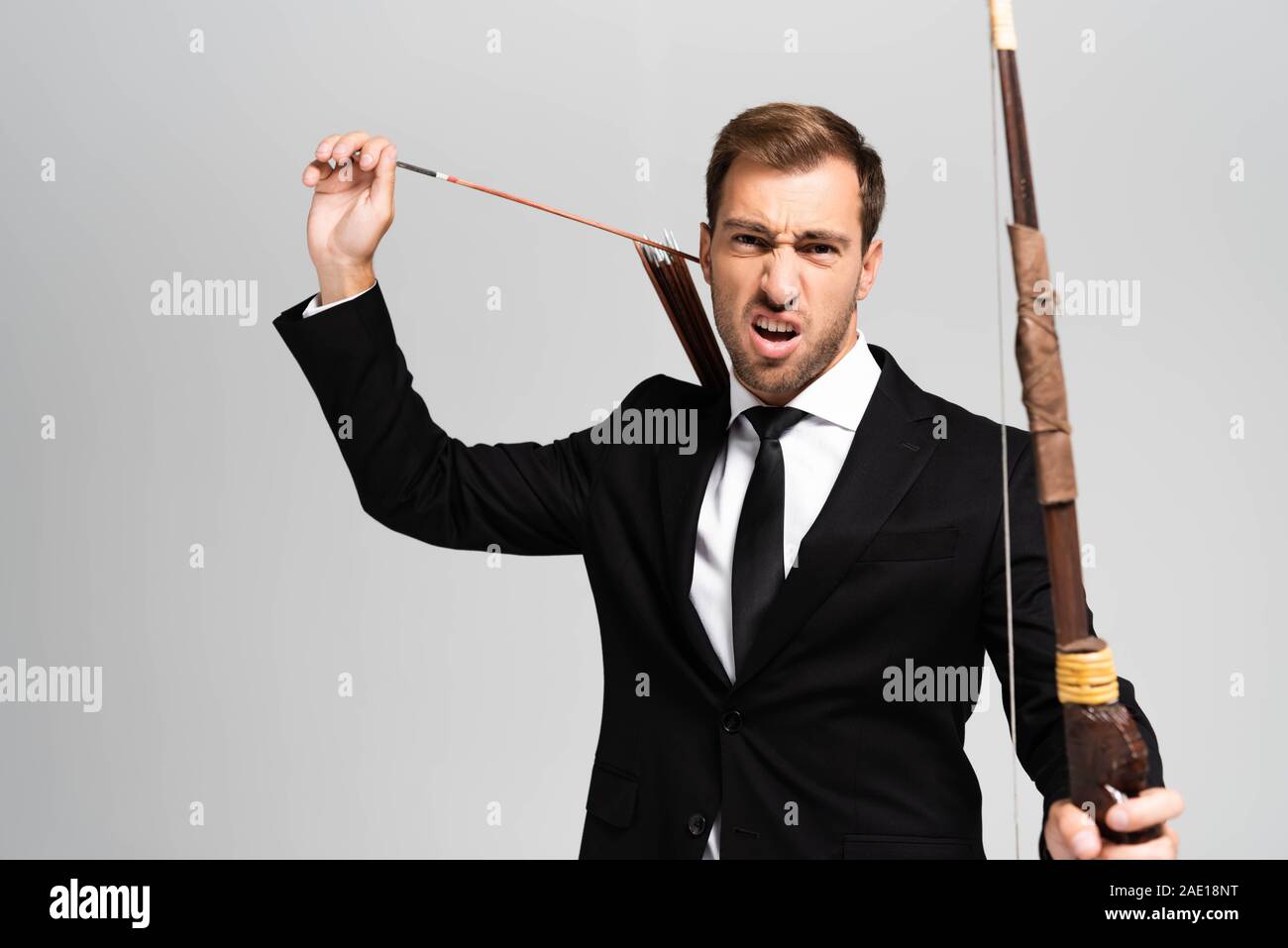 angry businessman in suit holding bow and arrow isolated on grey Stock ...