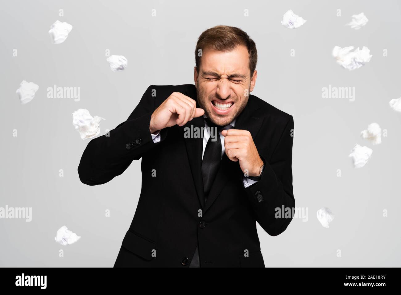 handsome and scared businessman in suit standing near falling crumpled ...