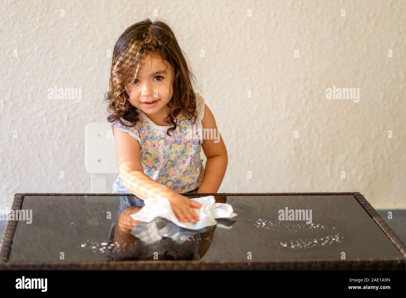Cute child help mom cleaning glass table. Little girl make cleaning in ...