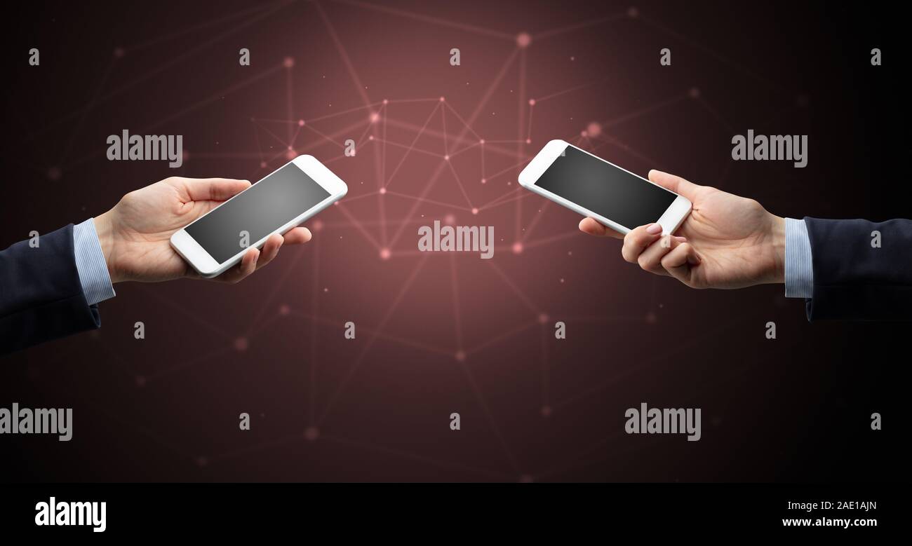 Close up of two hands holding smartphones to each other, wireless ...