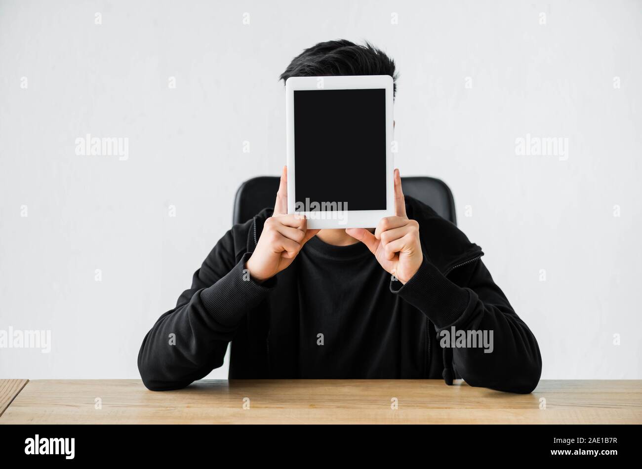 hacker obscuring face with digital tablet with copy space Stock Photo ...