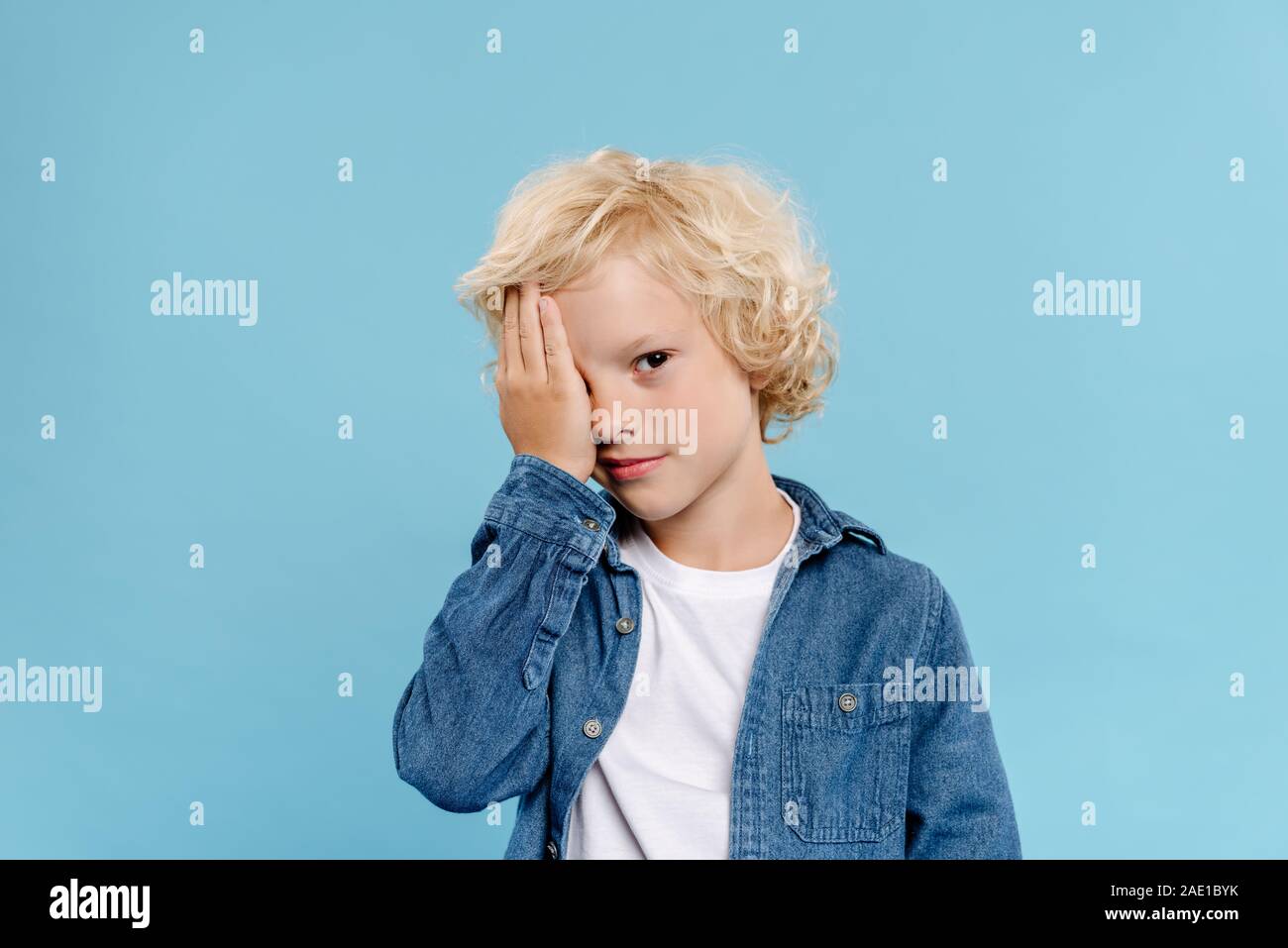 tired and cute kid obscuring face isolated on blue Stock Photo - Alamy