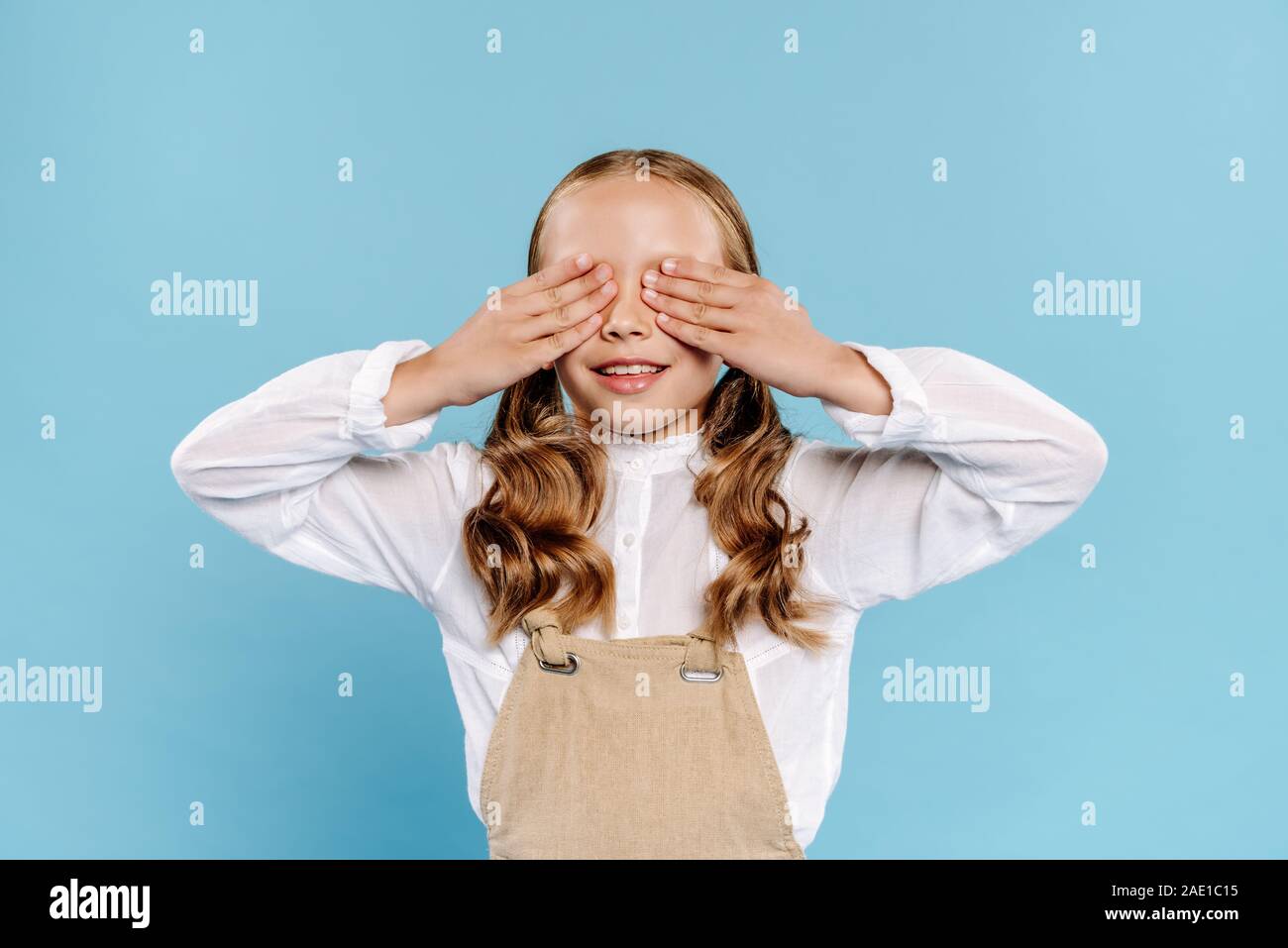 smiling and cute kid obscuring face isolated on blue Stock Photo - Alamy