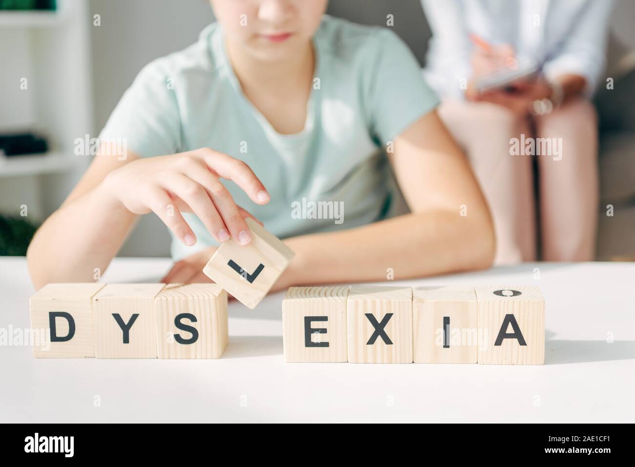 cropped view of kid with dyslexia sitting at table and playing with ...