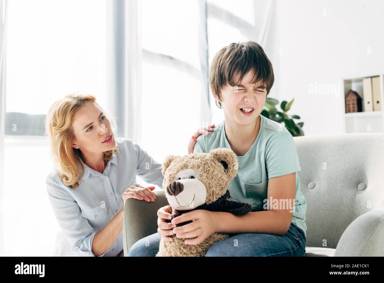 sad kid with dyslexia holding teddy bear and child psychologist talking ...