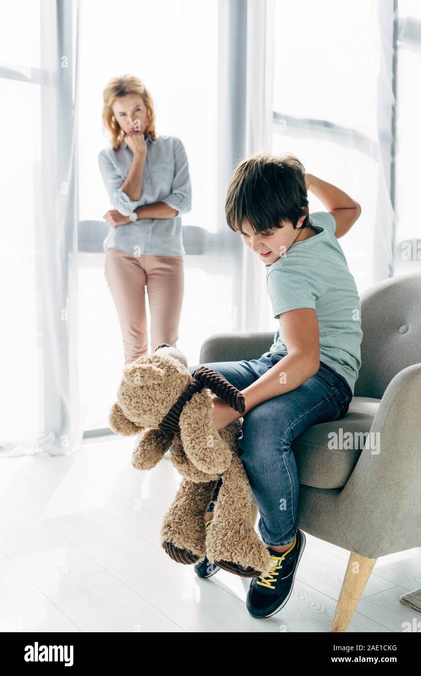 angry kid with dyslexia punching teddy bear and child psychologist ...