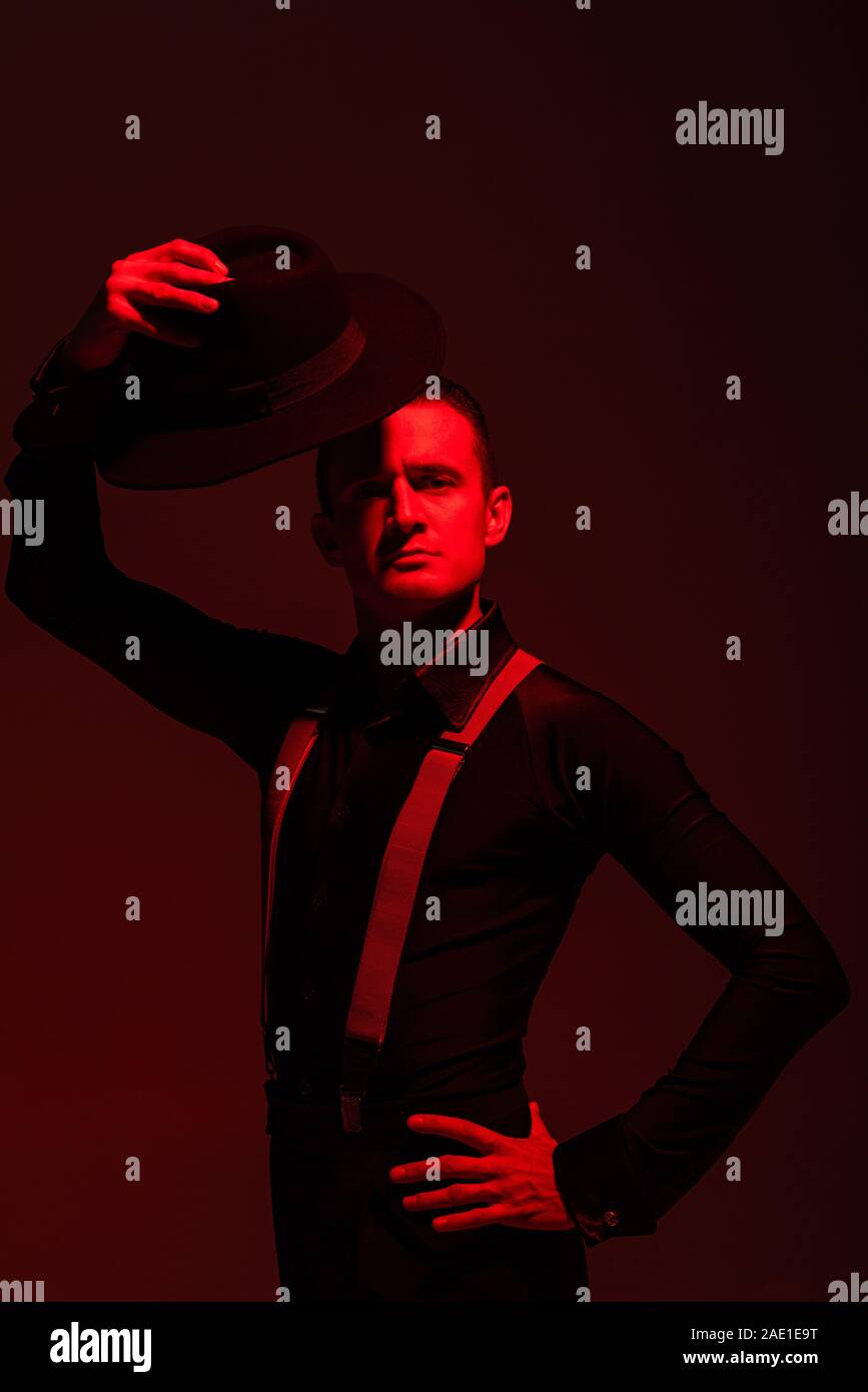 handsome tango dancer looking at camera and holding hat above head on ...