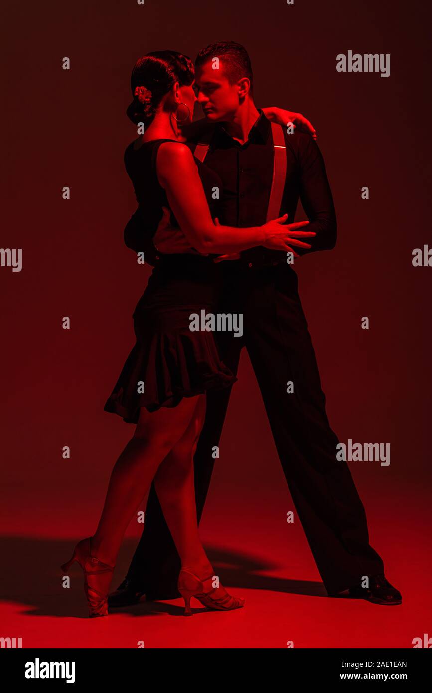 sensual couple of dancers performing tango on dark background with red ...
