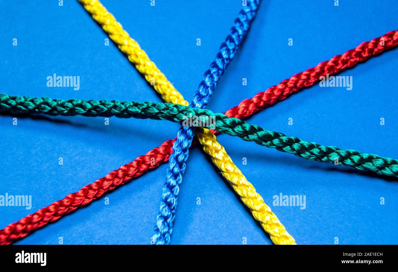 Colourful primary coloured string twisted on a bright blue background ...