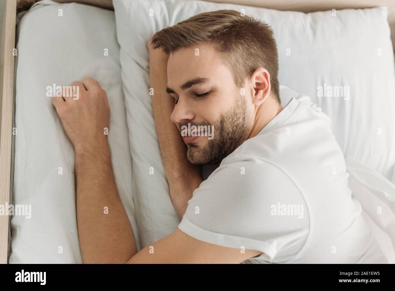 top view of young man smiling while sleeping on white bedding Stock ...