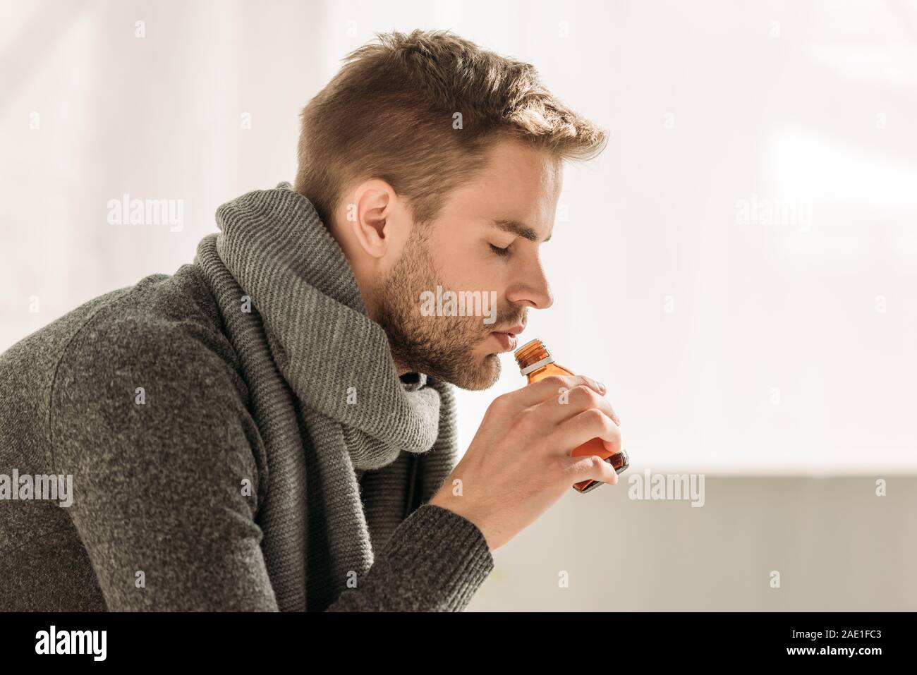 sick man in warm scarf drinking cough syrup with closed eyes Stock ...