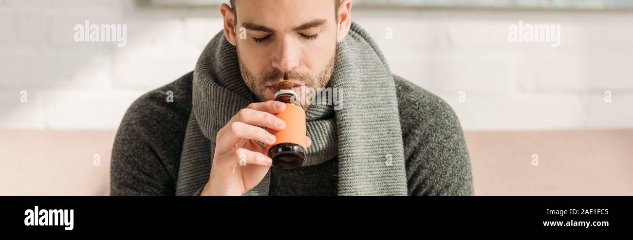 panoramic shot of diseased man drinking cough syrup with closed eyes ...