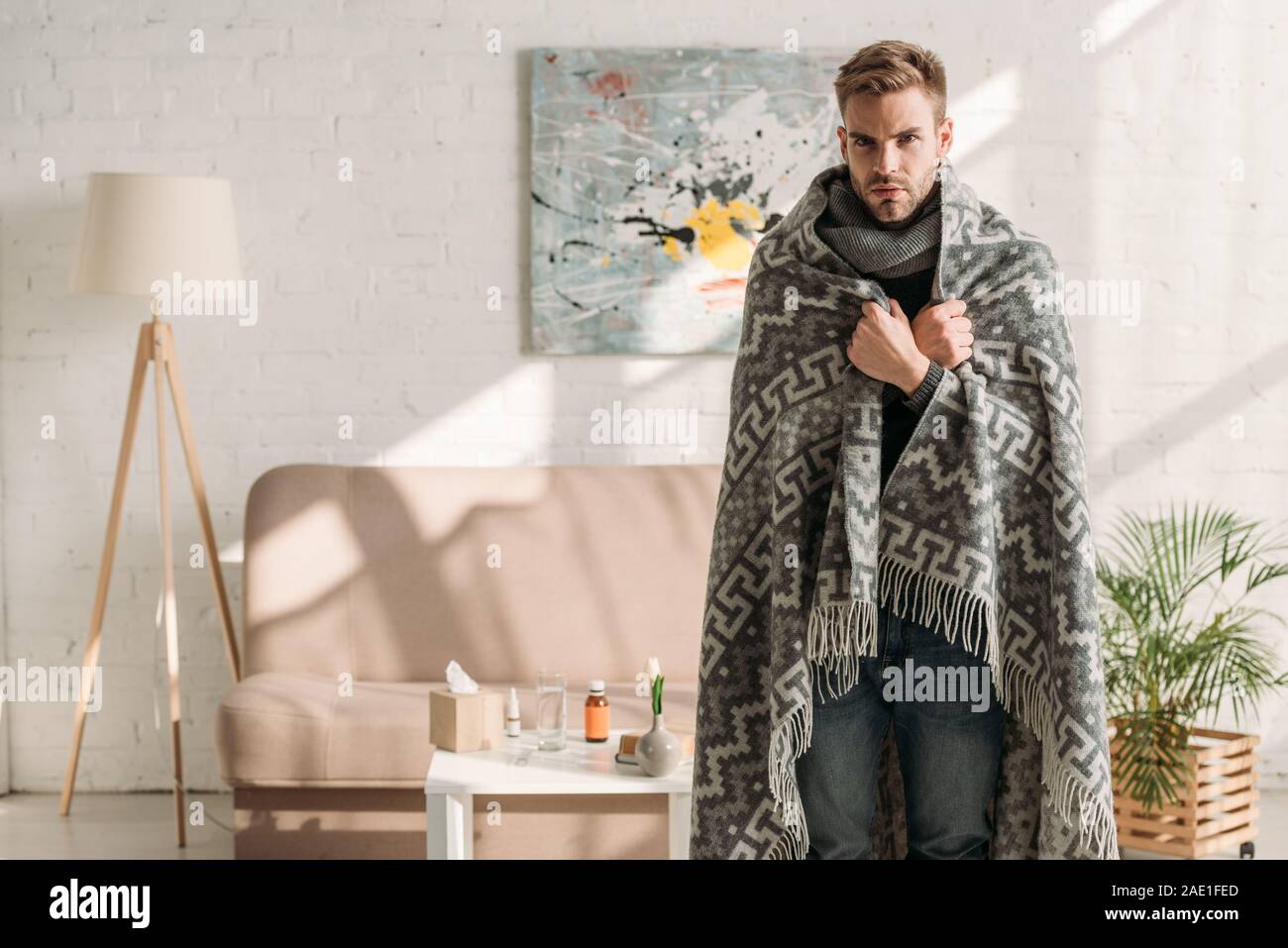 upset, sick man, wrapped in blanket, standing in room and looking at ...