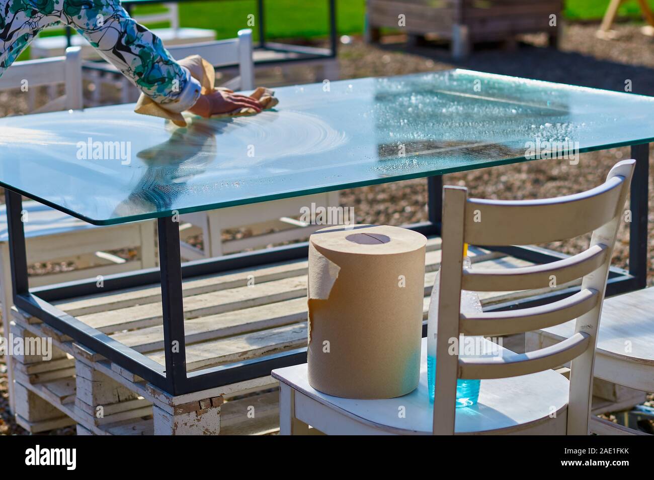 Cleaning the glass table with a chemical and a paper towel. On open air ...