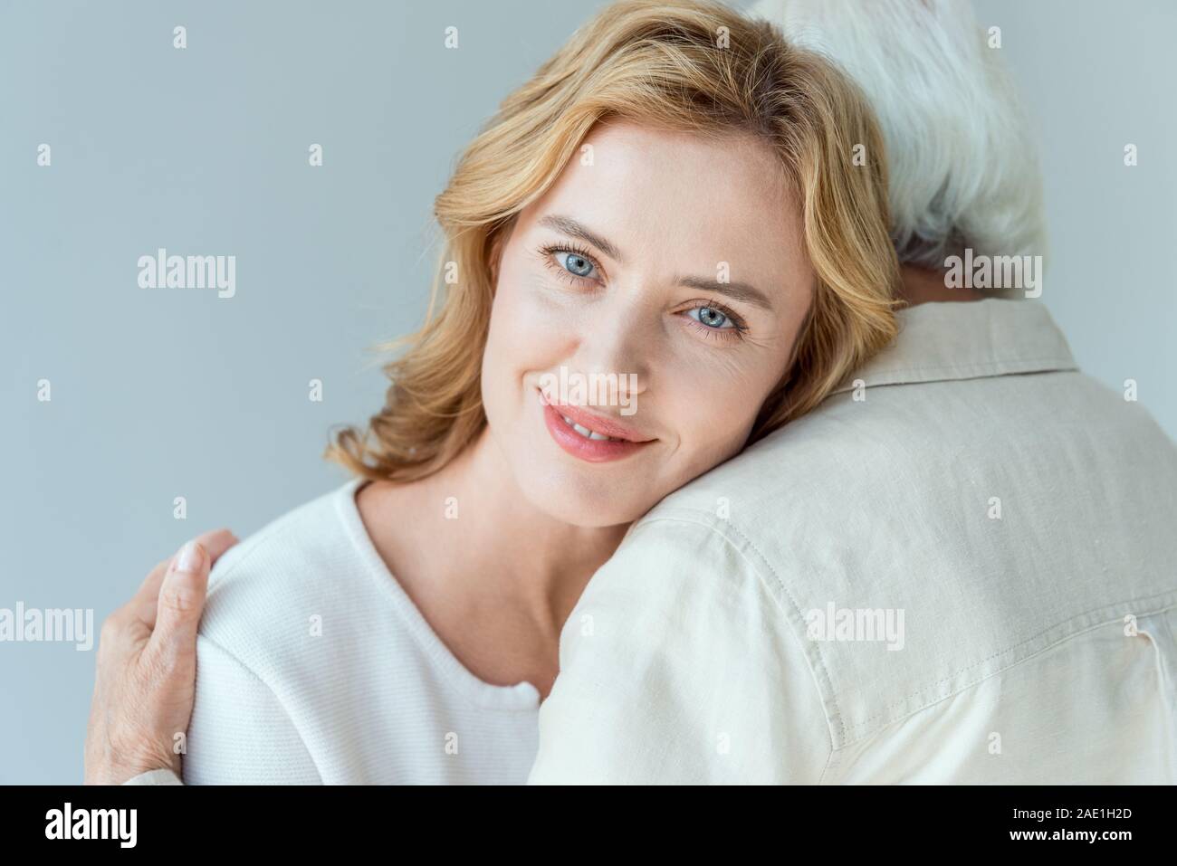 back view of mother hugging smiling daughter isolated on grey Stock ...