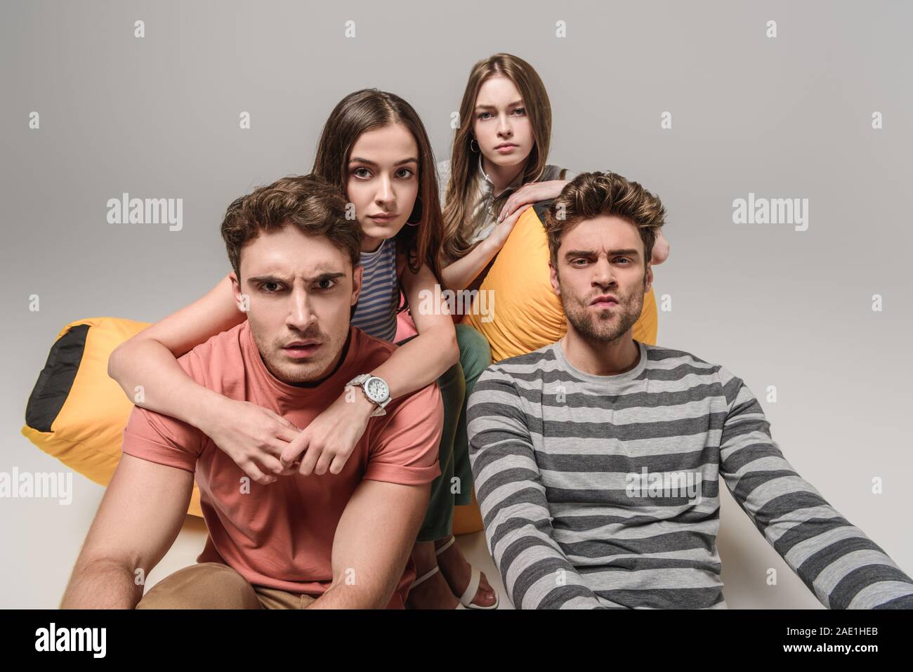 worried friends sitting on bin bag chair together, on grey Stock Photo ...