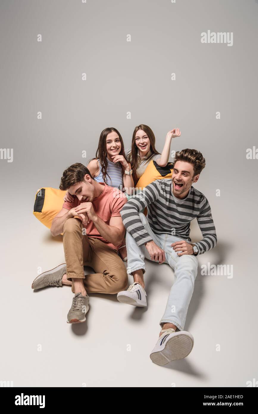 laughing friends sitting on bin bag chair together, on grey Stock Photo ...